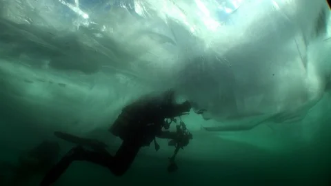 Diving under ice of cameraman underwater... | Stock Video | Pond5