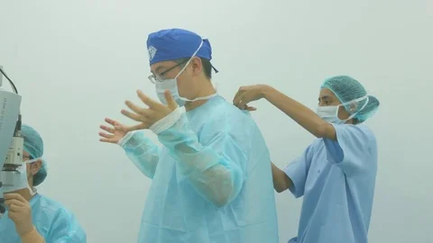 Doctor dressing up in a body suit in ope... | Stock Video | Pond5