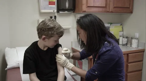 Doctor giving a shot to a young boy. | Stock Video | Pond5