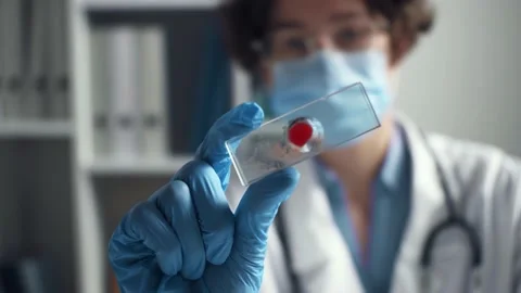 Doctor hand looks at drop of blood on gl... | Stock Video | Pond5