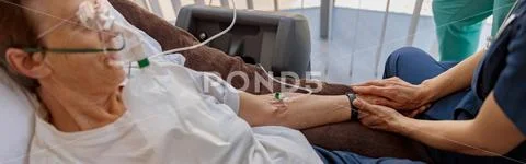 Doctor putting a drip in the arm of her patient in breathing mask ...