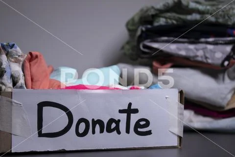'Donate' sign handwritten with black letters. A box with clothes and a ...