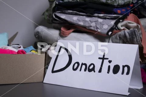 'donation' sign handwritten with black letters. A box with clothes and ...