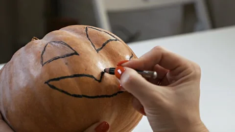 Drawing a funny face on a pumpkin with a... | Stock Video | Pond5
