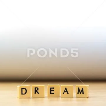 Dream word written in cube on wooden floor on white background, letter ...