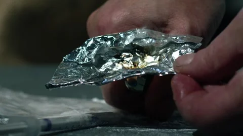 Drug addict burning heroin in foil | Stock Video | Pond5