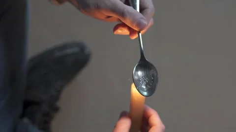 A drug addict cooks heroin on a spoon wi... | Stock Video | Pond5