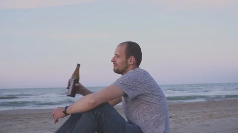 Drunk man drinking beer on the sea beach... | Stock Video | Pond5