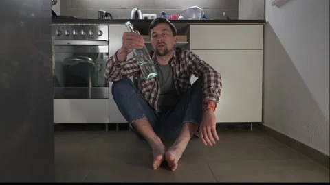 Drunk sad man sitting on kitchen floor d... | Stock Video | Pond5