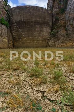 Dry swamp bottom with cracked earth, in the background the dam without ...