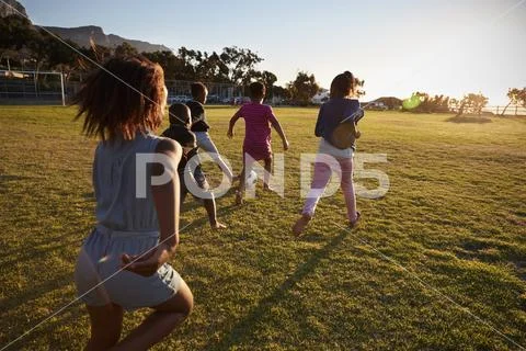 Elementary school kids playing football in a field, back view Stock ...
