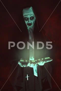 An evil cursed nun with a bible and a cross in her hands looks at the ...