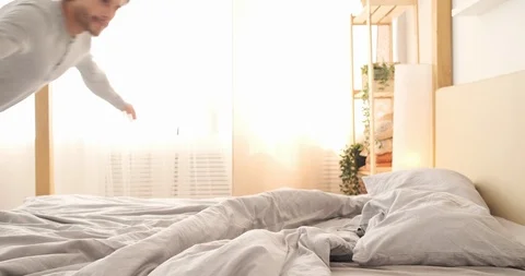 Exhausted man jumping on bed to sleep | Stock Video | Pond5