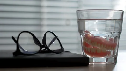 False teeth in glass of water on table w... | Stock Video | Pond5