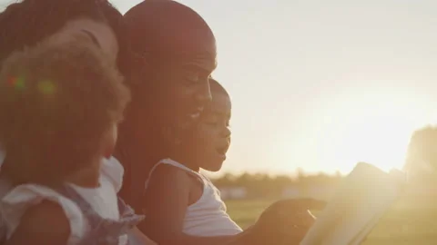 Family Sitting in the Sun Reading a Book | Stock Video | Pond5