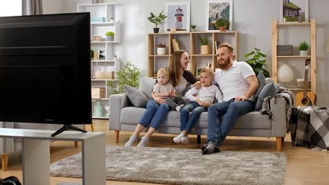Family watching TV while sitting on a co... | Stock Video | Pond5