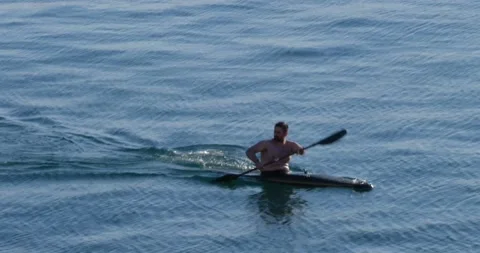 A fat man rowing a canoe shirtless on th... | Stock Video | Pond5