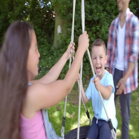 Father Pushing Children On Tire Swing In... | Stock Video | Pond5