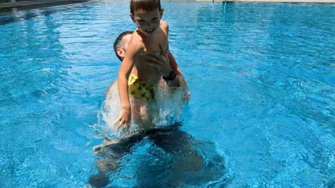 Father throw son in swimming pool. Dad a... | Stock Video | Pond5