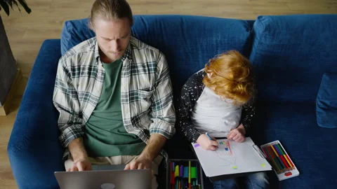 Father types on laptop and boy draws hou... | Stock Video | Pond5