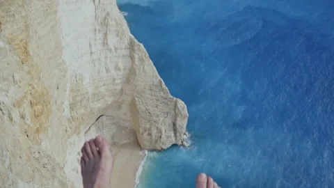 Feet dangling off edge of cliff panning ... | Stock Video | Pond5