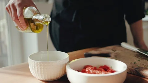 Female chef pouring olive oil into a bow... | Stock Video | Pond5