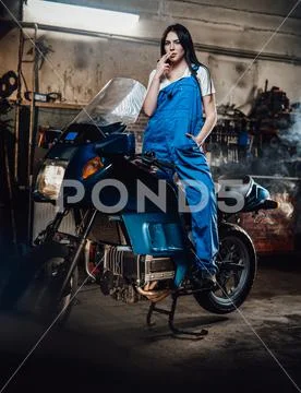 Female mechanic relaxing smoking a cigarette while standing on ...