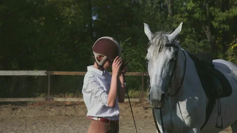 Female rider in riding clothes takes off... | Stock Video | Pond5
