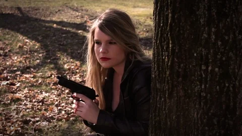Female Secret Agent hides behind tree wi... | Stock Video | Pond5