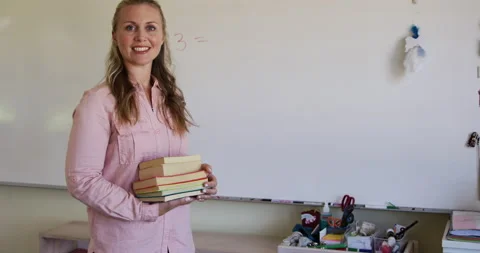 Female teacher holding stack of books in... | Stock Video | Pond5