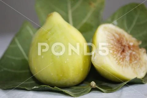 Photograph: Fig cut in half with another whole fig on a leaf, photo of ...