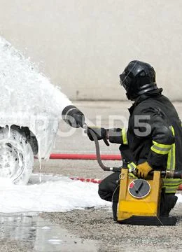 Firefighter extinguishing a car fire using a special white flame ...