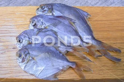 Five dry salted piranha fish lie on their side on a wooden board. view ...