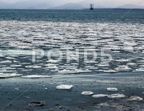 Photograph: Floating ice with oil rig in the background #11669712