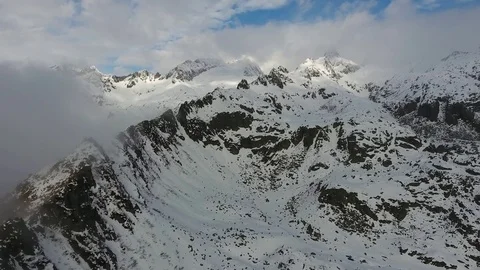 Flying in clouds between snow-capped mou... | Stock Video | Pond5