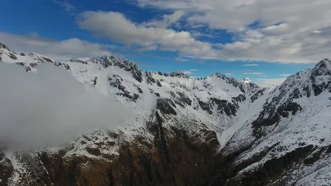 Flying in clouds between snow-capped mou... | Stock Video | Pond5