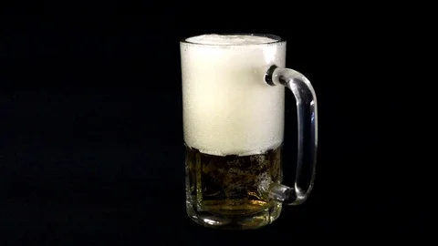 A foaming mug of beer on a dark backgrou... | Stock Video | Pond5