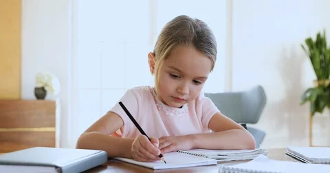 Focused cute little kid girl doing homew... | Stock Video | Pond5