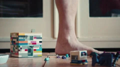 Foot stepping on lego brick, messy floor... | Stock Video | Pond5