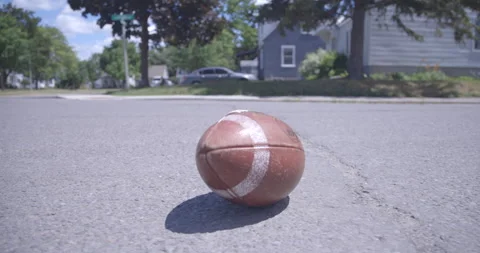 Football rolling to a stop in the street... | Stock Video | Pond5