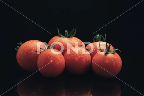Fresh six tomato on a black glass table and dark background. Stock ...