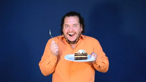 Funny fat man in orange shirt eat a cake... | Stock Video | Pond5