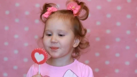 Funny little girl eating a candy with a ... | Stock Video | Pond5