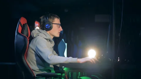 Gamer sits on a chair, playing on pc, si... | Stock Video | Pond5