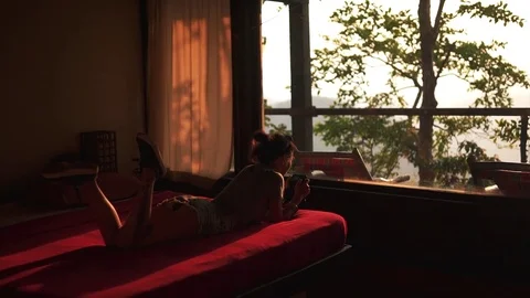 Girl on a bed in bedroom looking pics in... | Stock Video | Pond5