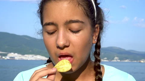 Girl chewing potato chips on the backgro... | Stock Video | Pond5