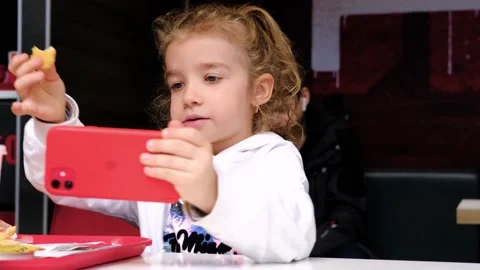 The girl eat at the KFC and watch cartoo... | Stock Video | Pond5