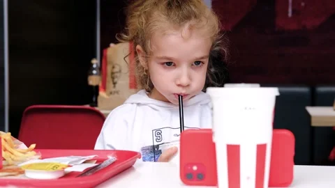 The girl eat at the KFC and watch cartoo... | Stock Video | Pond5