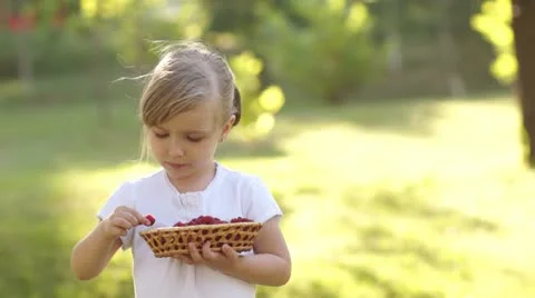 Girl eating raspberry and holding a bask... | Stock Video | Pond5