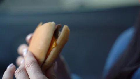 Girl eats a cheeseburger in a car | Stock Video | Pond5